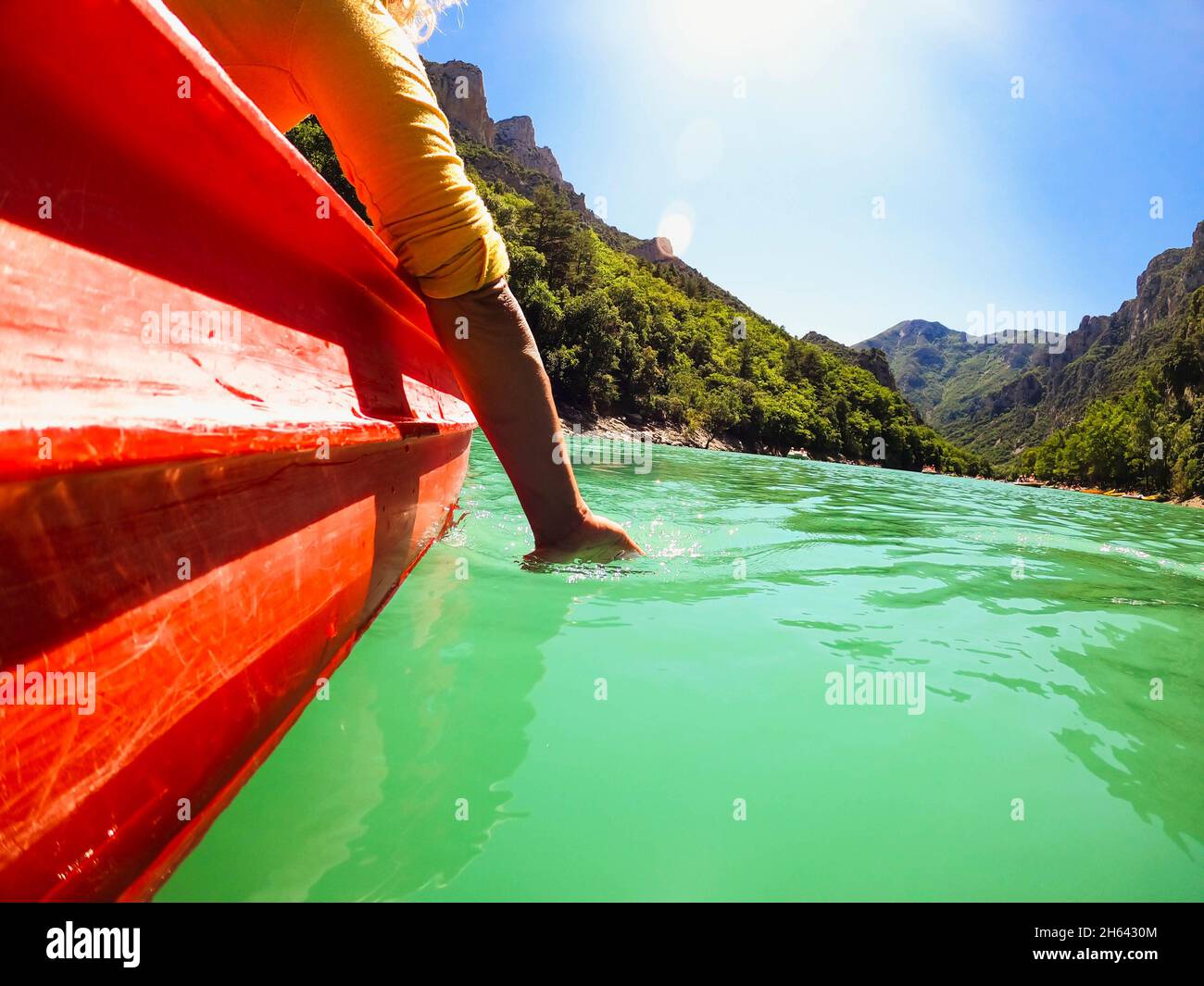 woman traveler enjoying her kayak ride on canyon with hand dipping ...
