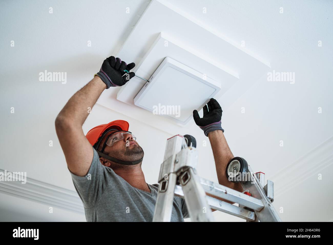 Latino electrician installing a led light on the ceiling Stock Photo ...