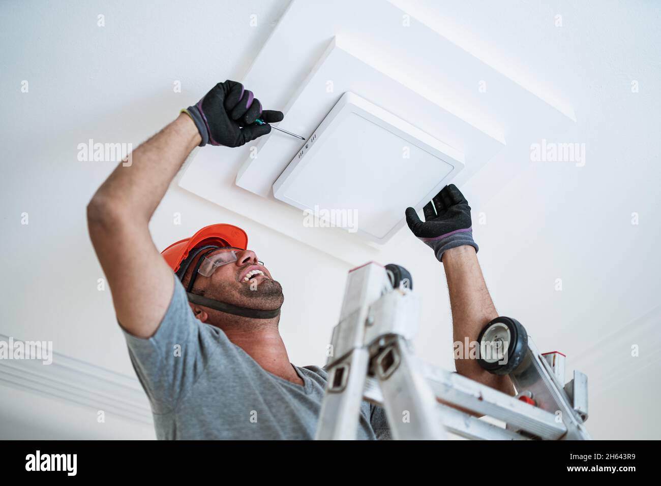 Latino electrician installing a led light on the ceiling Stock Photo ...