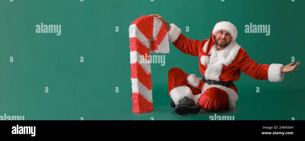 Santa Claus with candy cane pinata on green background with space for ...
