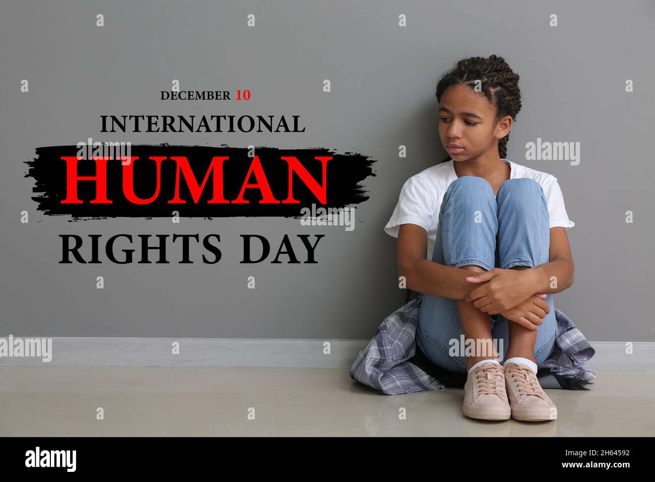 Sad African-American girl sitting near grey wall. International Day of ...