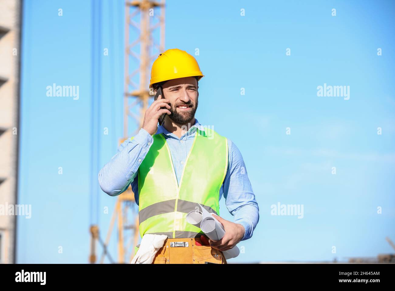 Construction worker talking by mobile phone outdoors Stock Photo - Alamy