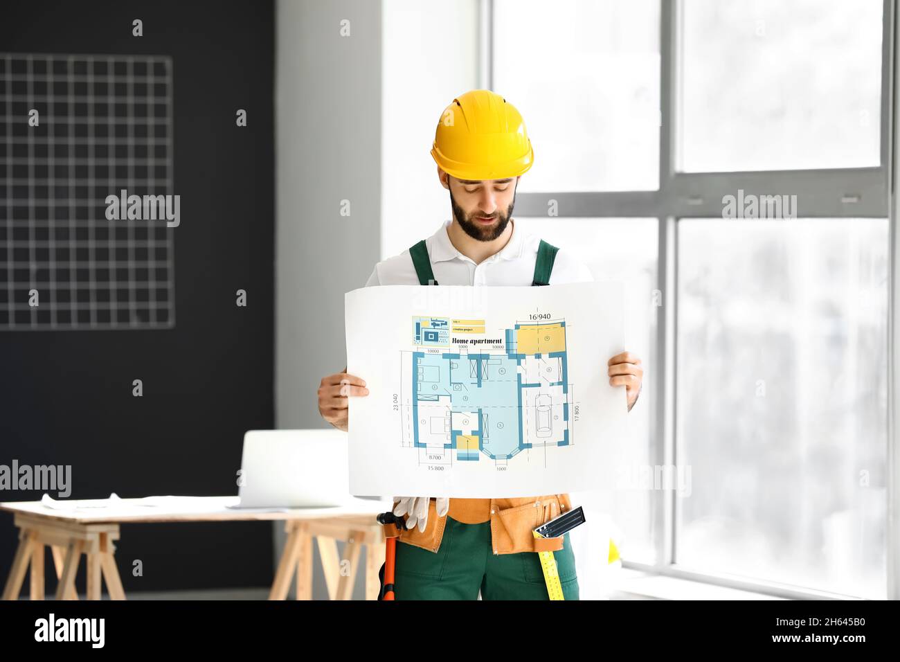 Construction worker with house plan in room Stock Photo - Alamy