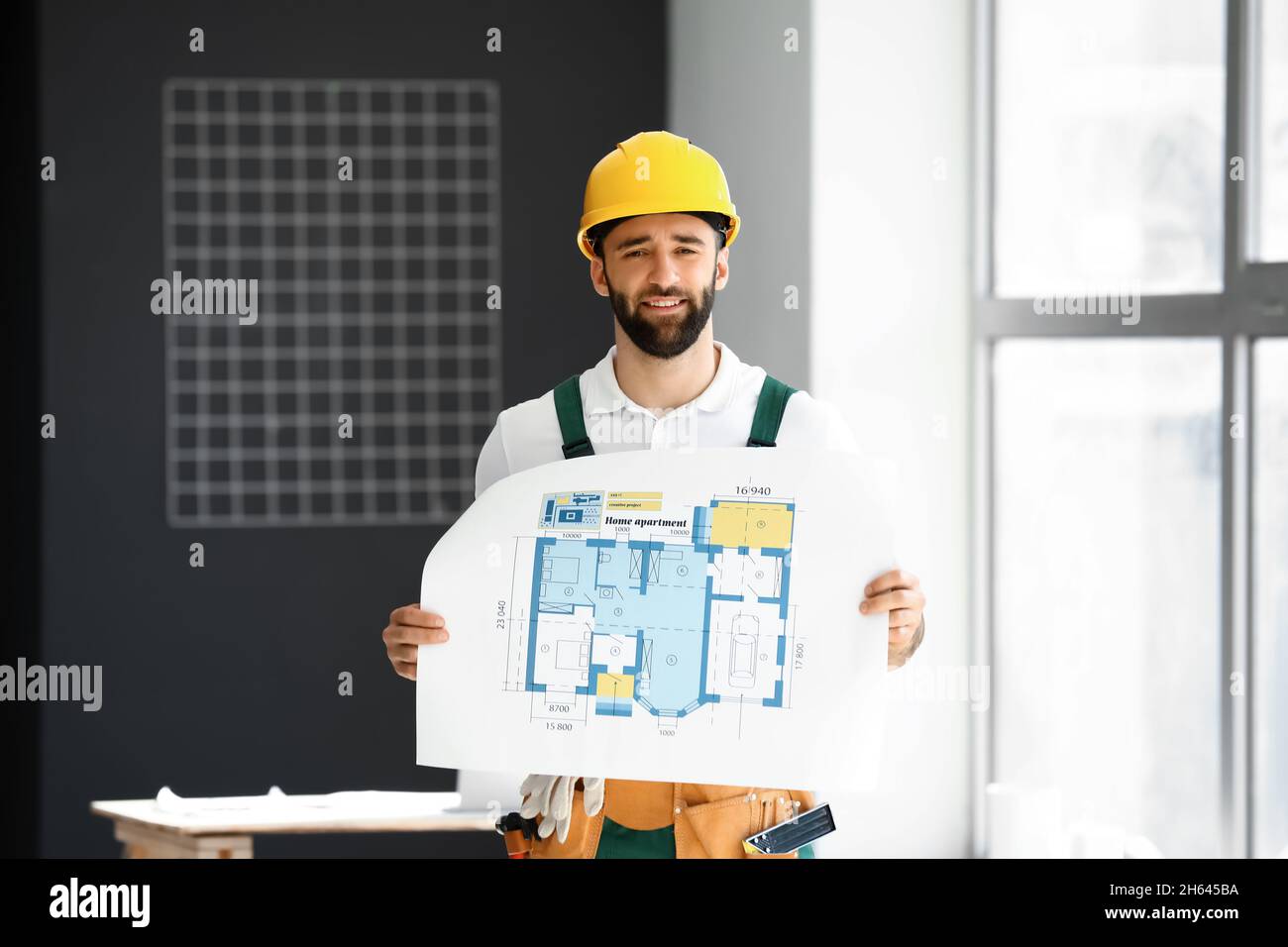 Construction worker with house plan in room Stock Photo - Alamy