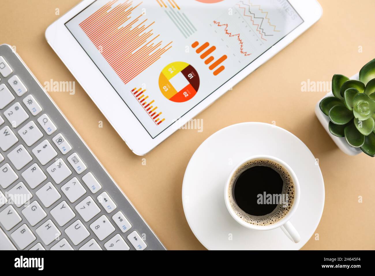 Tablet computer with charts, cup of coffee and computer keyboard on ...