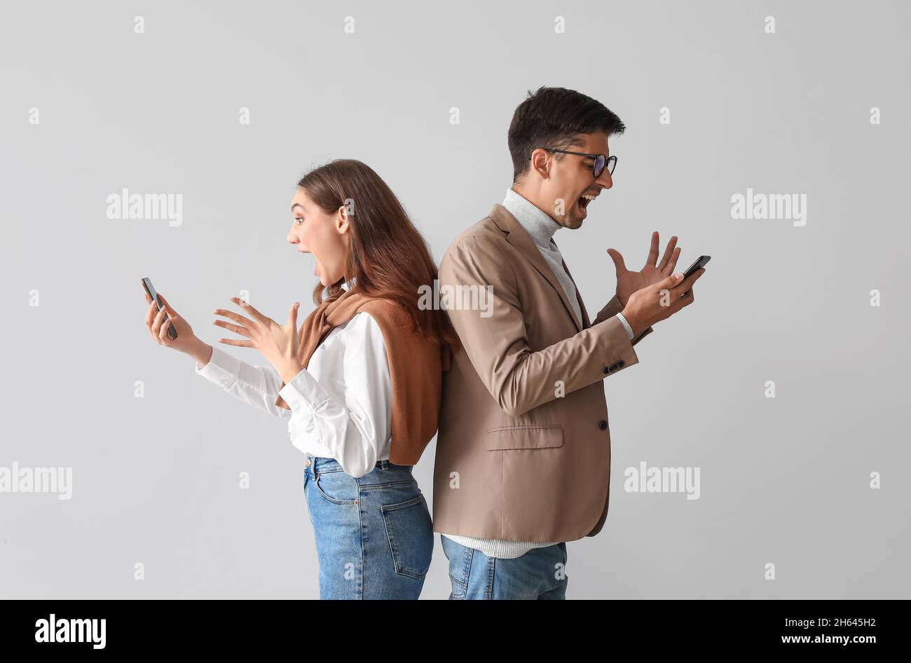 Angry young couple with mobile phones on light background Stock Photo ...