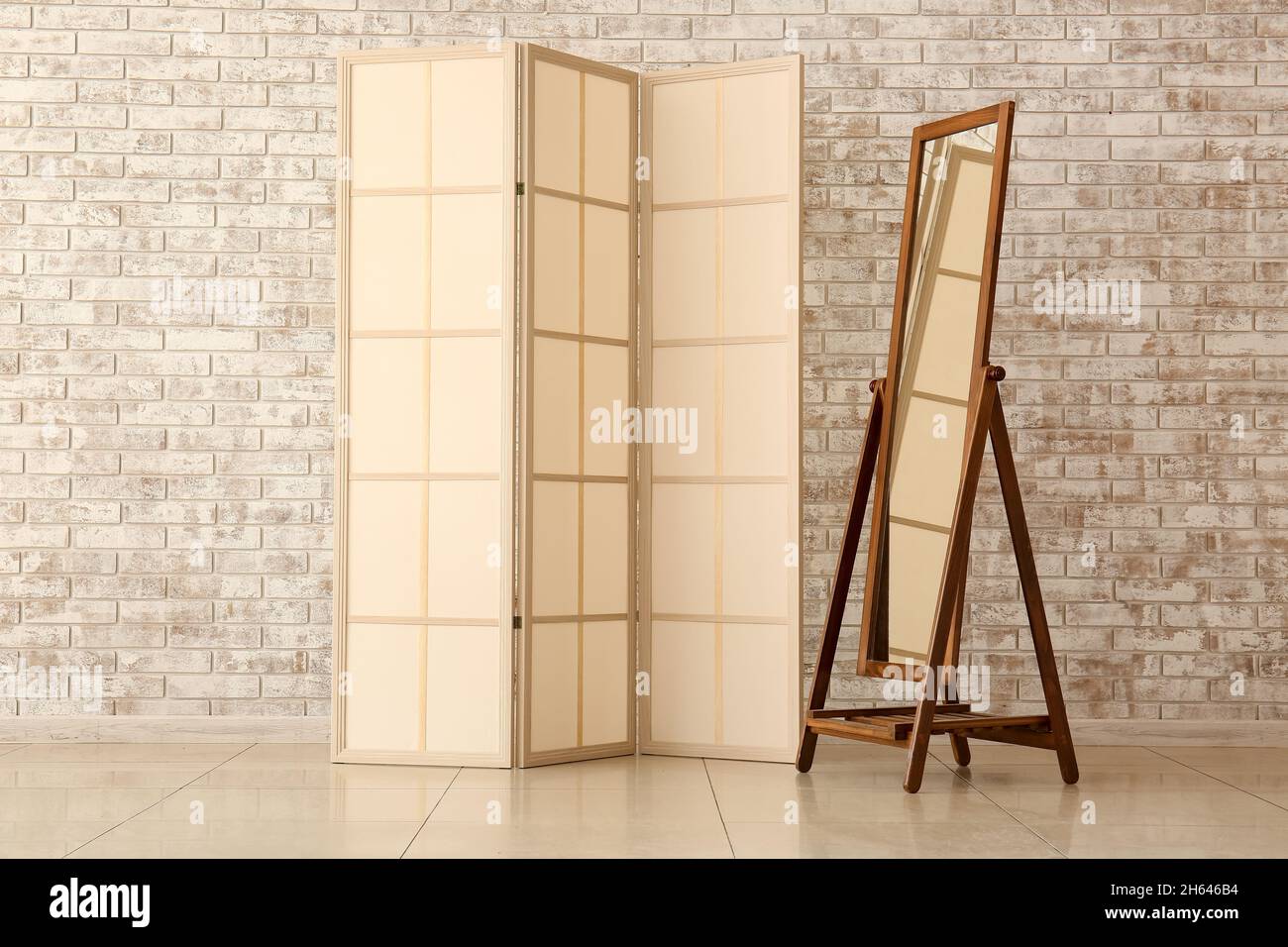 Beige folding screen and mirror near light brick wall Stock Photo - Alamy