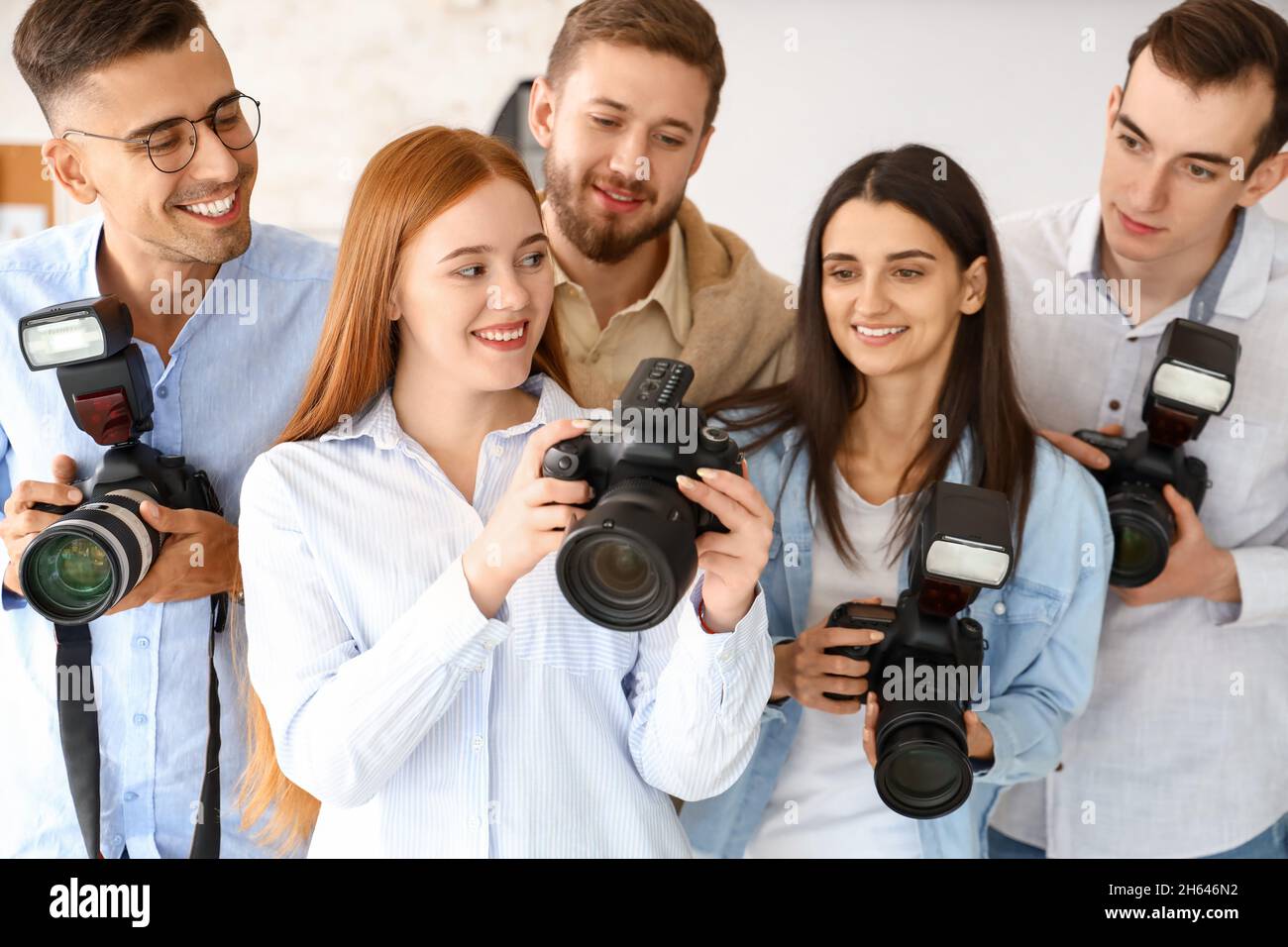 Professional photographer teaching young people in studio Stock Photo ...