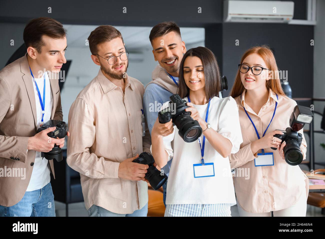 Professional photographer teaching young people in studio Stock Photo ...