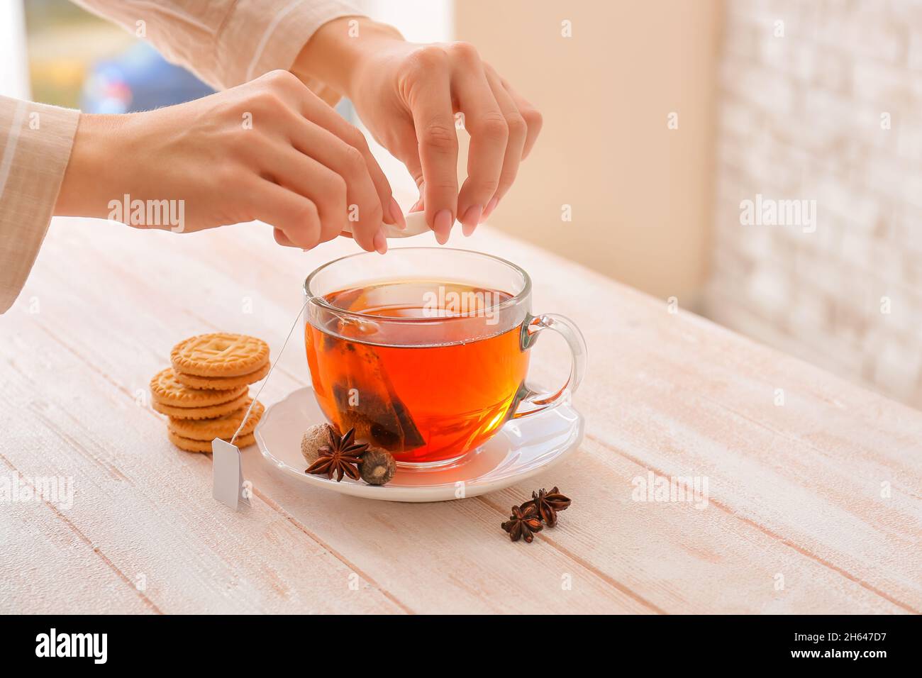 Woman adding sugar into glass cup with hot tea at table in cafe Stock ...