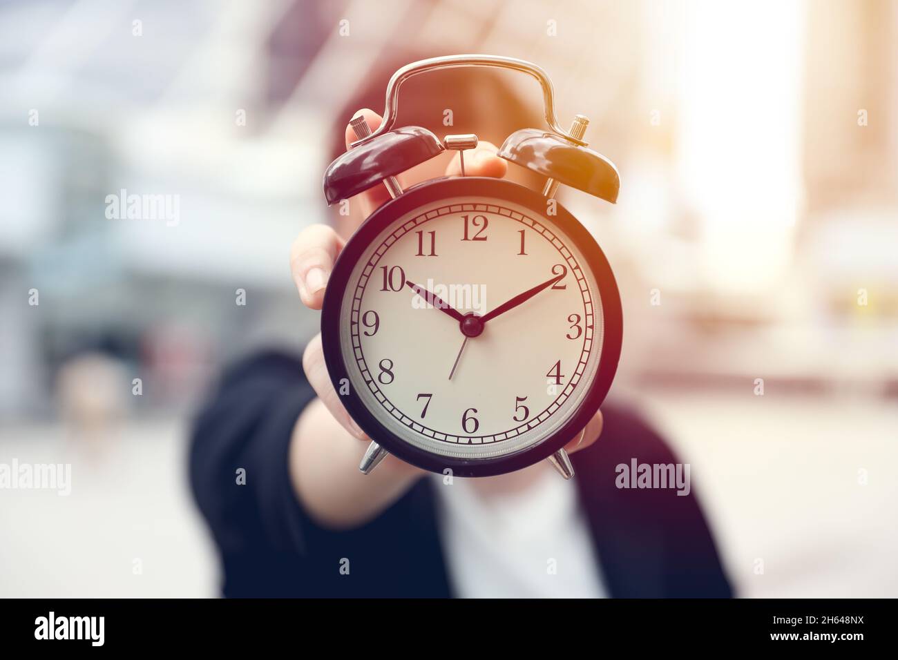 closeup business people hand holding alarm bell clock outdoor blur ...