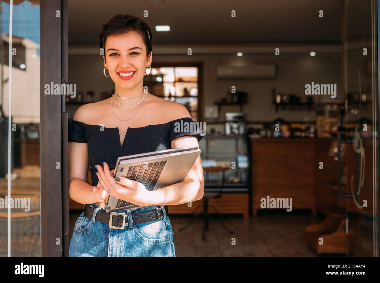 Portrait of happy Latin woman standing at doorway of her store ...