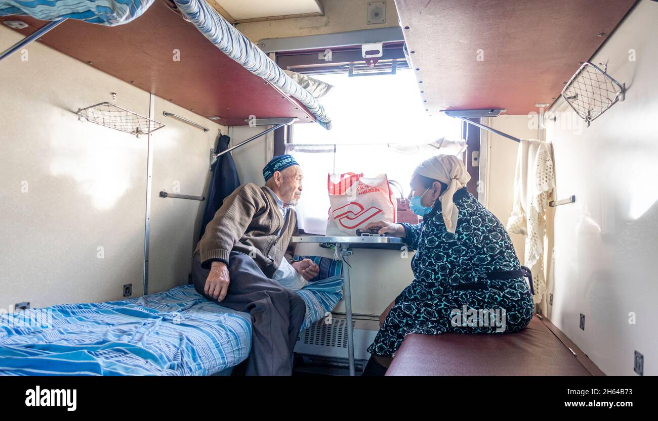 Elderly Kazakh man and woman sitting in the 3 class car looking out the ...