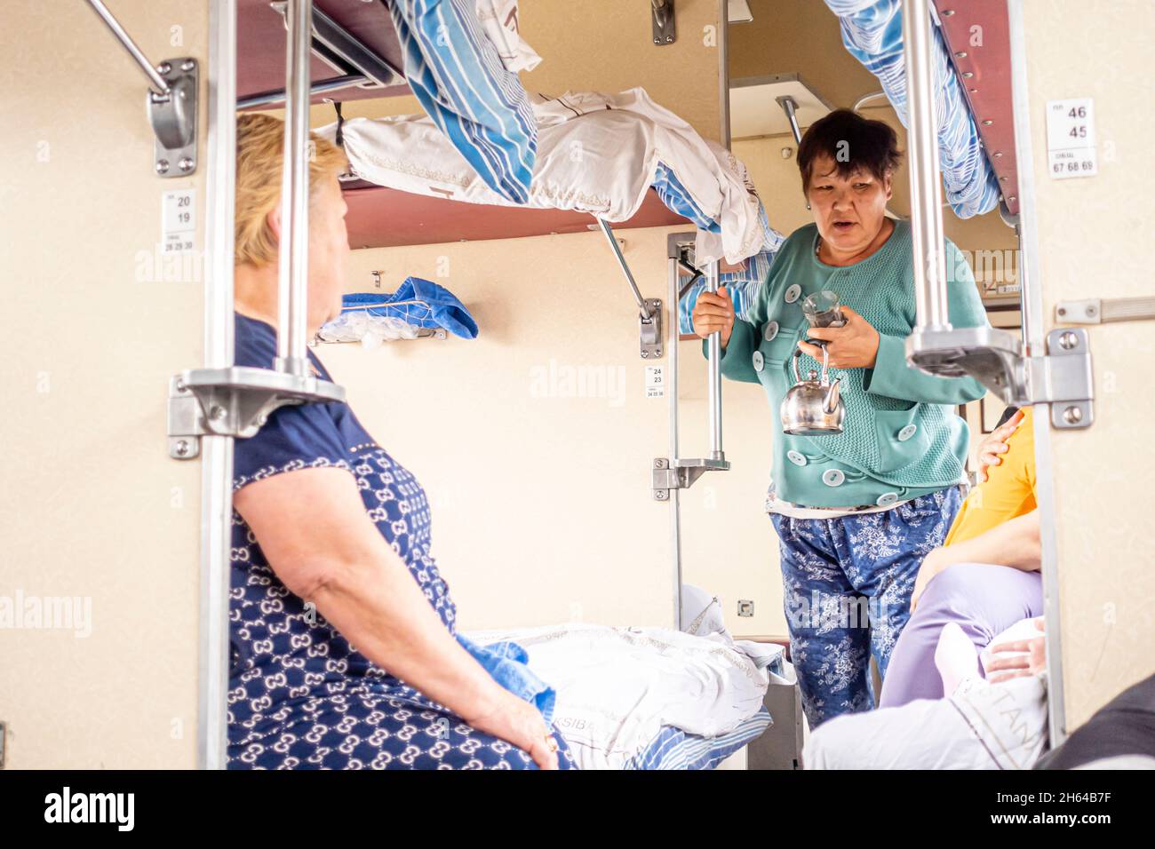A Kazakh woman passing with a kettle in a 3 class car, platzcart ...