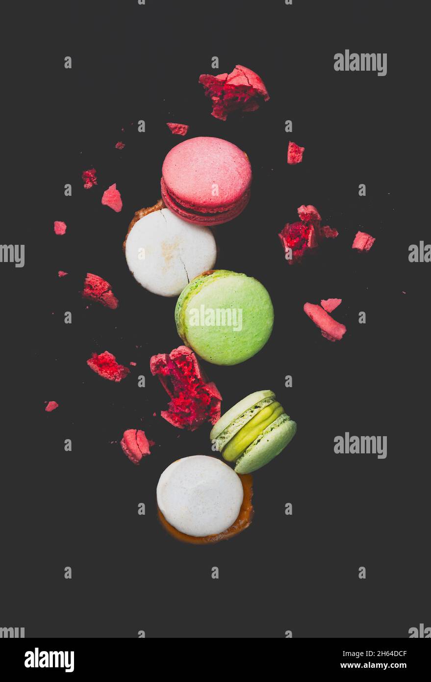 Different types of macaroons in motion falling on black background ...