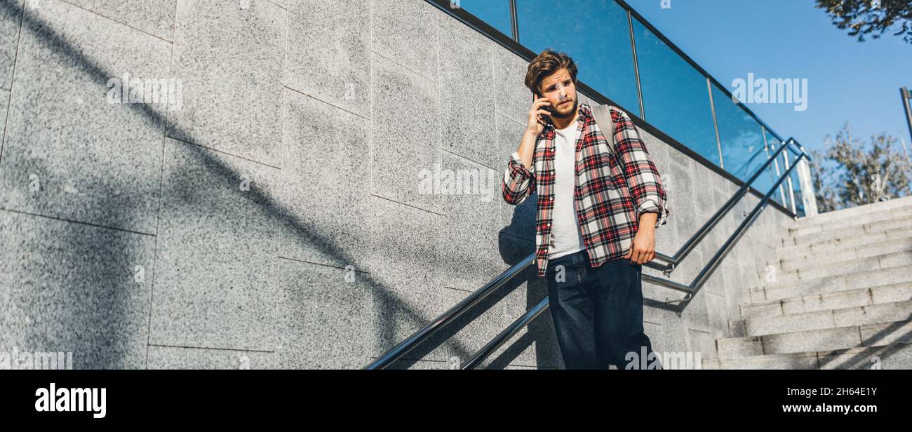 Portrait of modern handsome young man speaking on phone. Hipster guy ...
