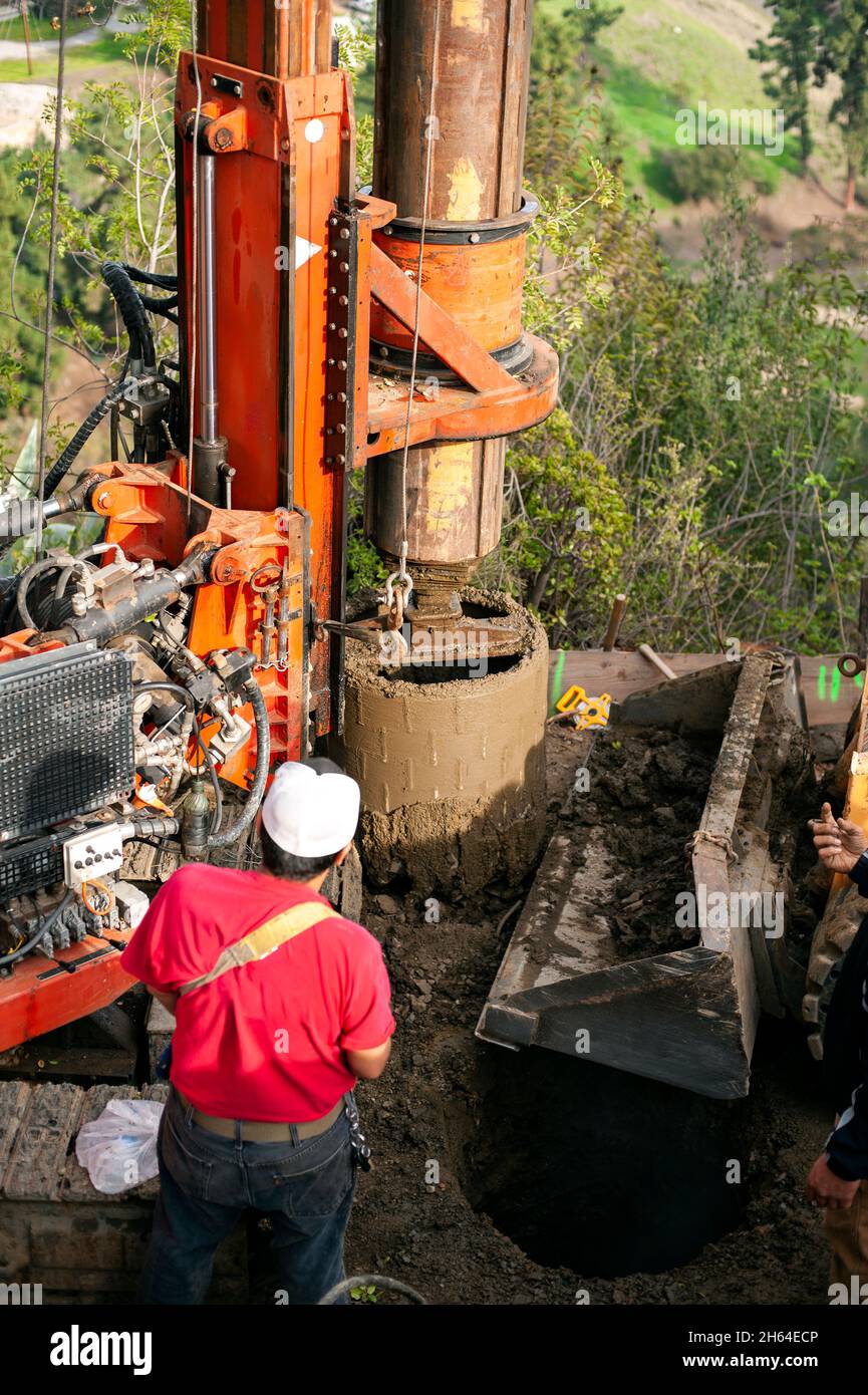 Remote controlled excavator boring a deep hole in the earth for new ...