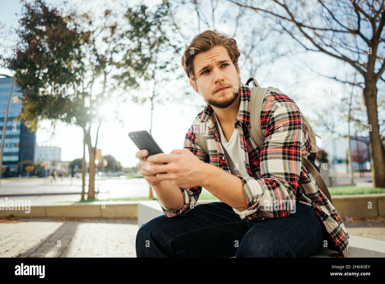 Portrait of modern young man with smartphone on a street. Hipster guy ...