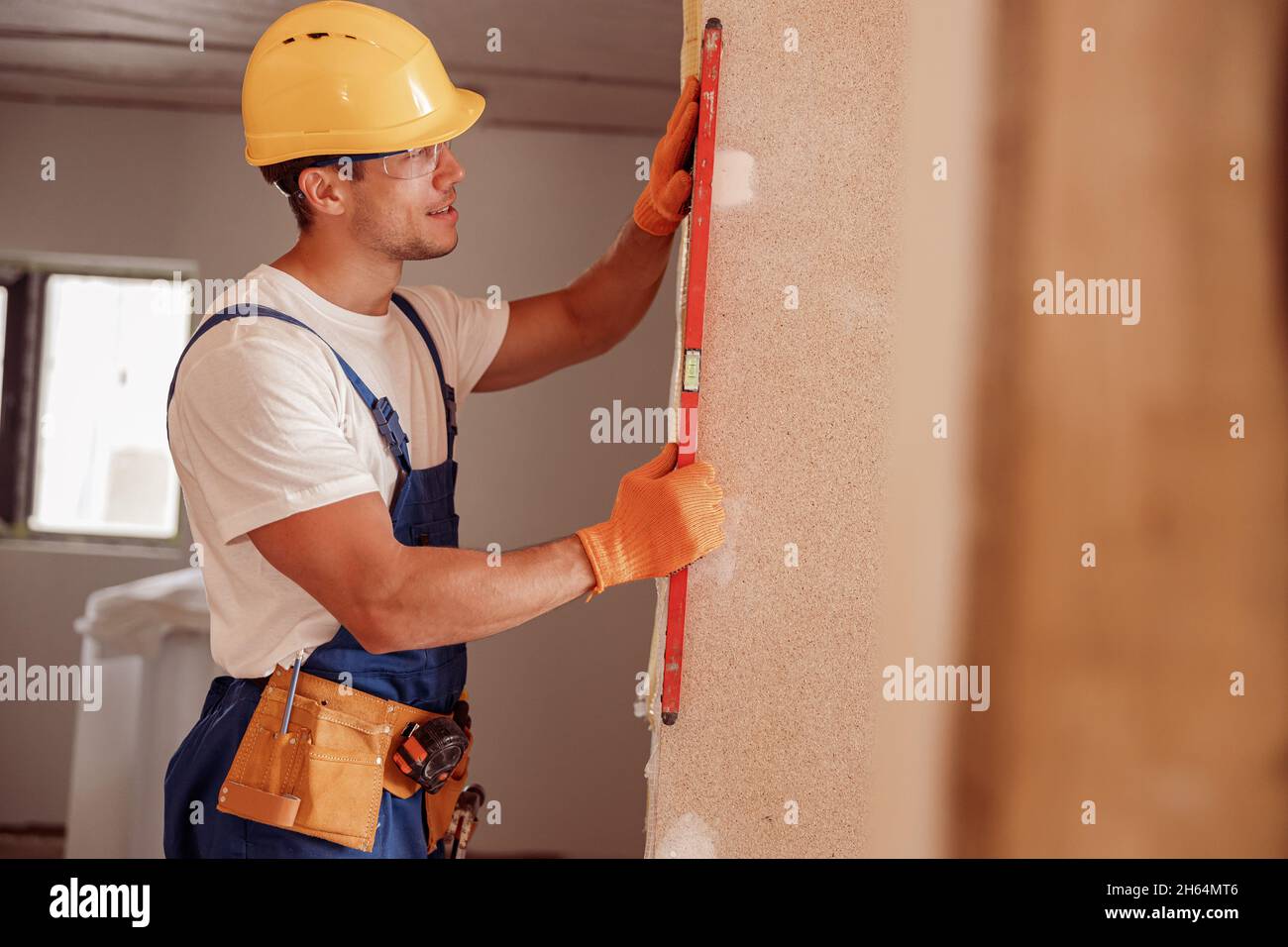 Joyful male builder measuring wall in house Stock Photo - Alamy