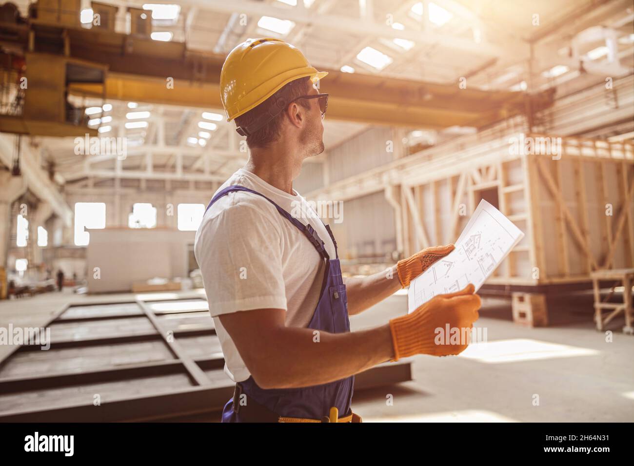 Architect working at house building construction site with blueprint ...