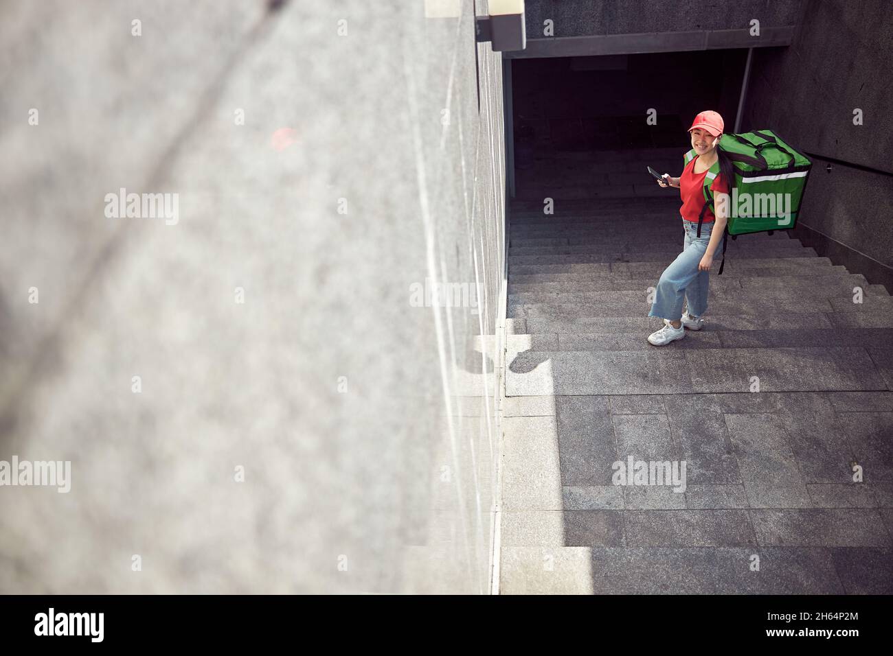 Female courier delivering food order through city Stock Photo - Alamy