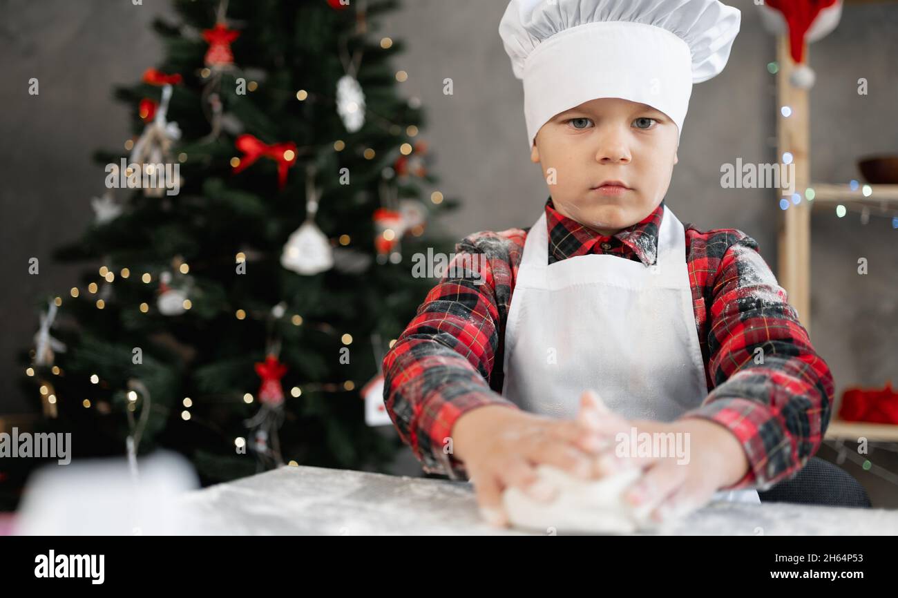 Portrait of a little baker in uniform making bread dough. Boy prepares ...