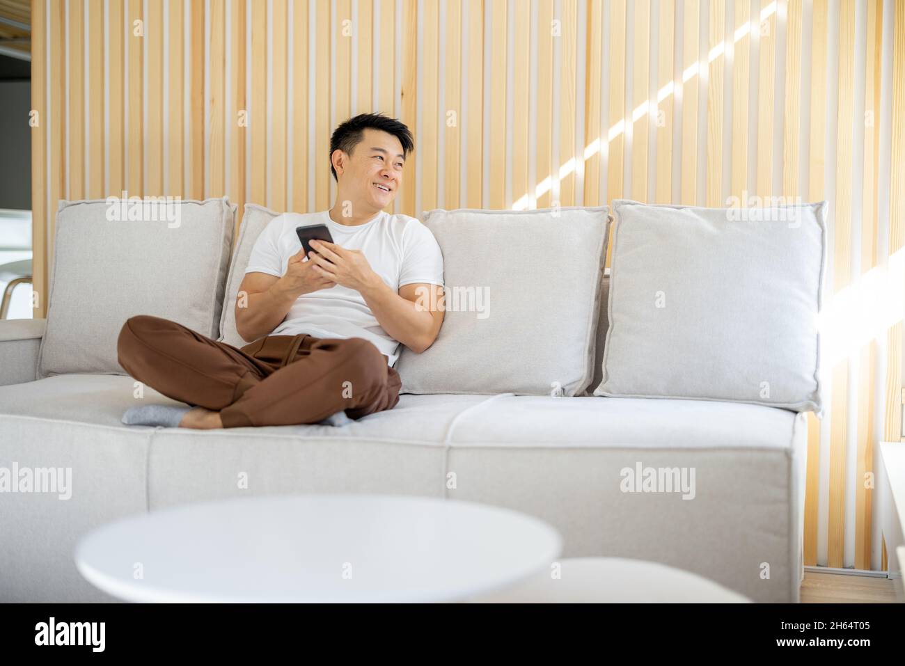 Man using smartphone and looking in window at home Stock Photo - Alamy