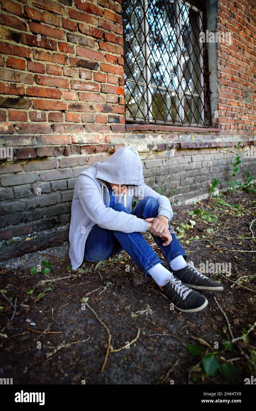 Sad Teen sit near the Brick Wall of the Old House Stock Photo - Alamy