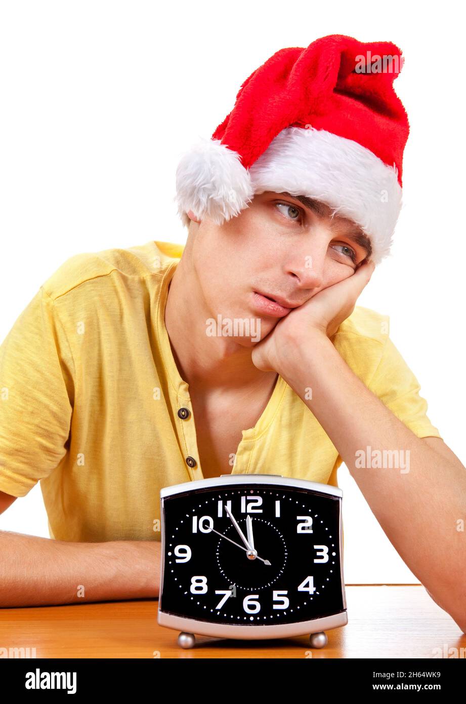 Bored Young Man in Santa's Hat with the Clock at the Table On The White ...