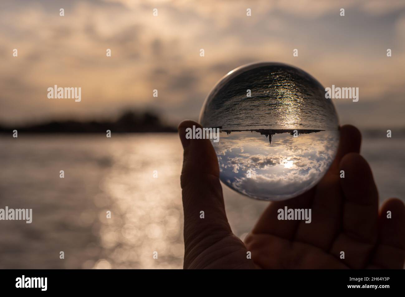Hand holding glass sphere in front of sunset in Venice (Italy ...