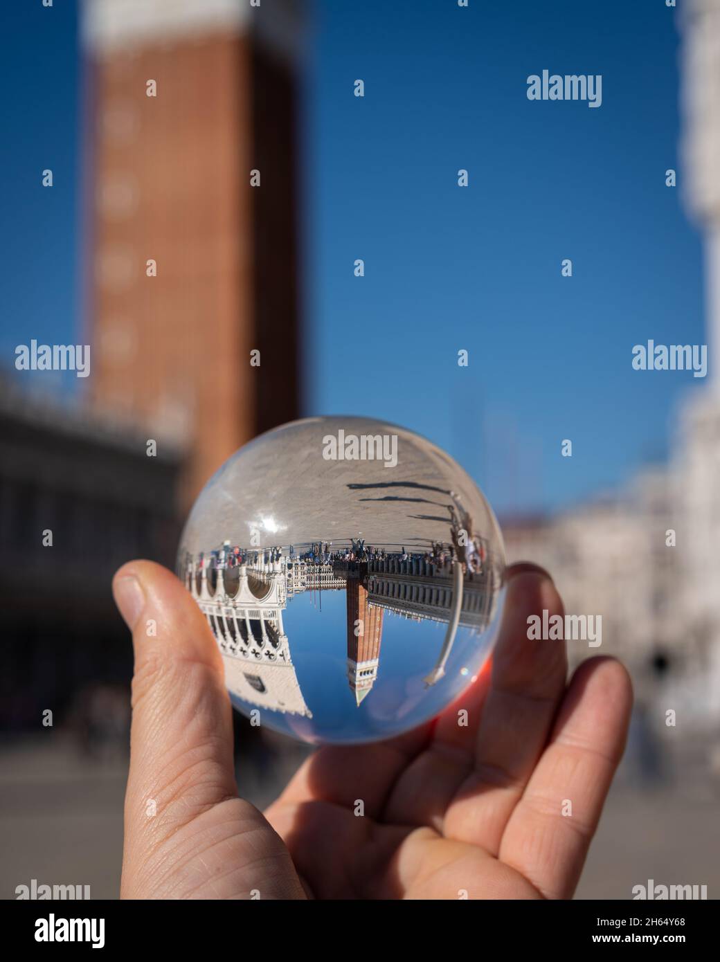 Hand holding glass sphere in front of doge palace and Campanile in ...