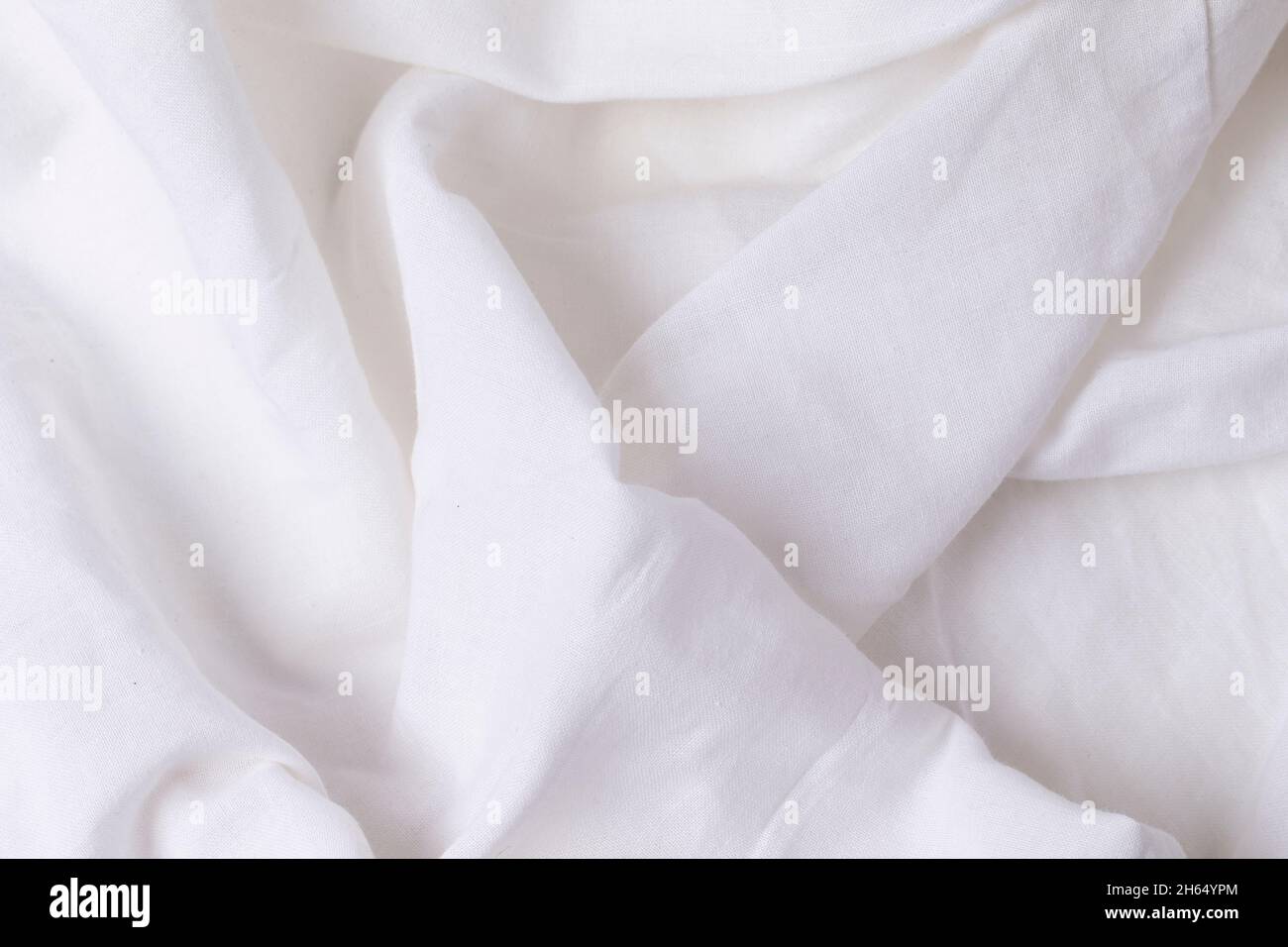 A fragment of crumpled white fabric as a background texture.Crumpled ...