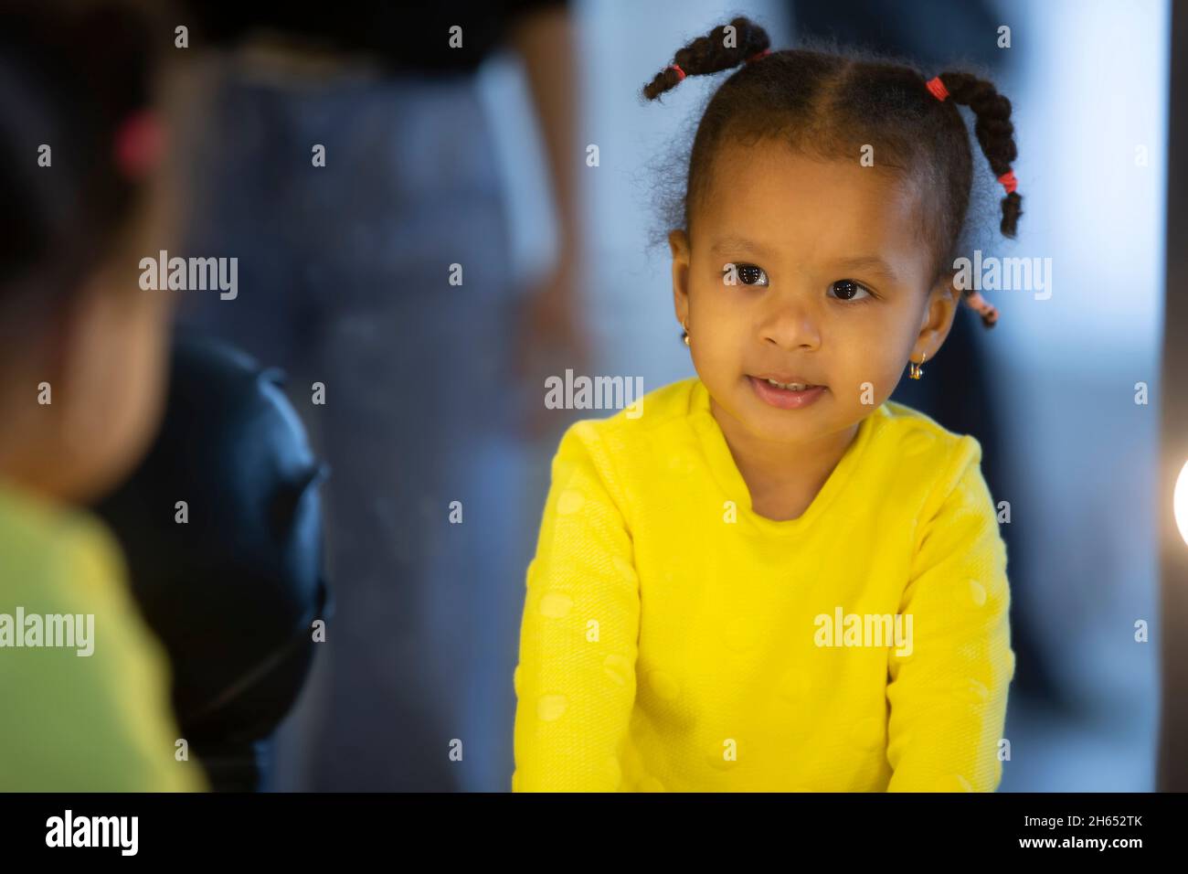 Little African American girl looks at her reflection in the mirror ...