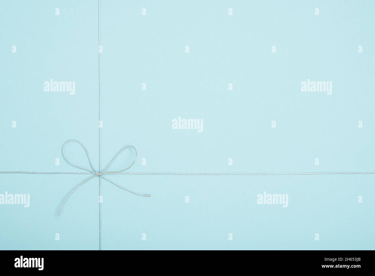 Shiny silver string tied in a bow on blue pastel background Stock Photo ...