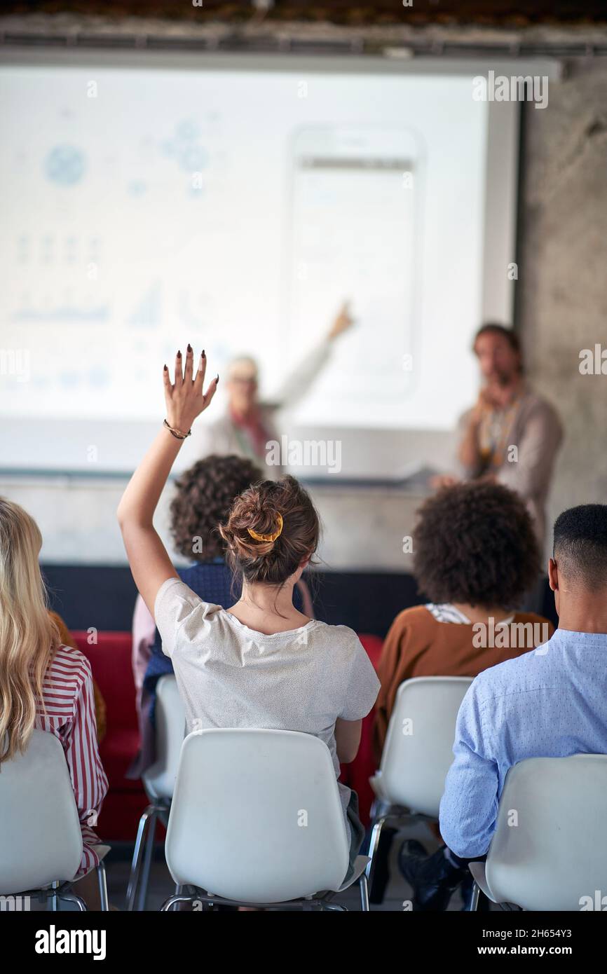 A young woman is asking a question during a presentation in a pleasant ...