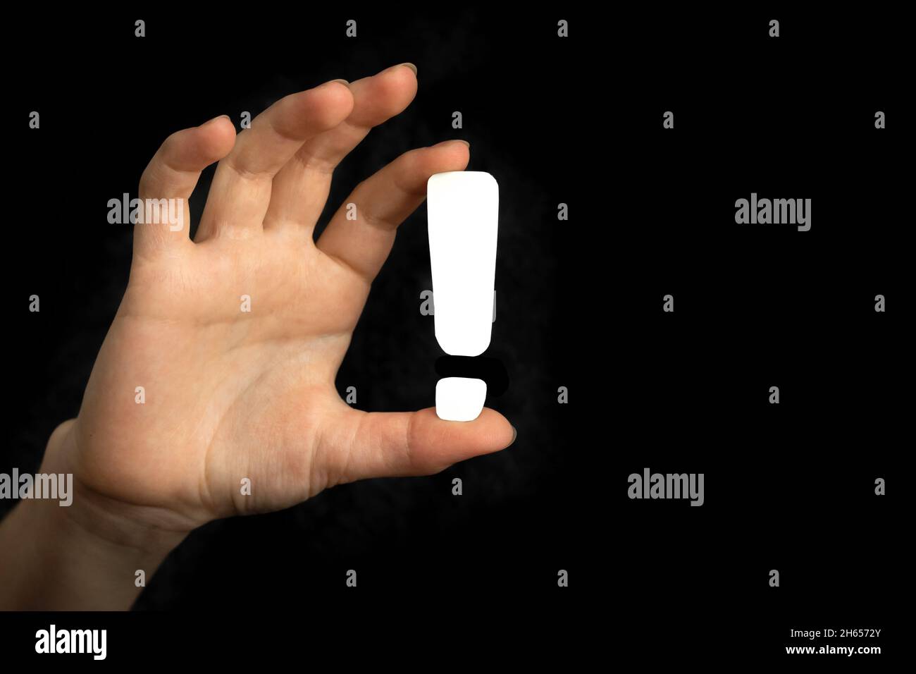 Exclamation sign in hand on a black background. Exclamation mark ...