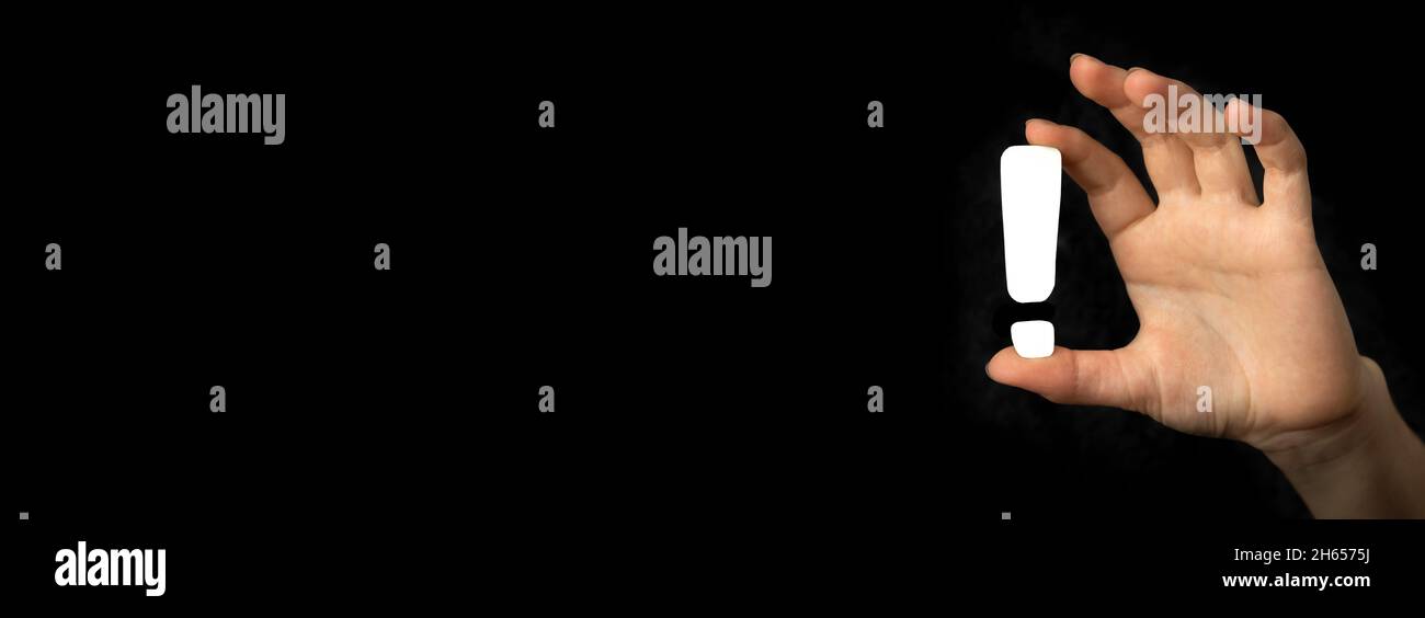 Exclamation sign in woman hand on a black background. Exclamation mark ...