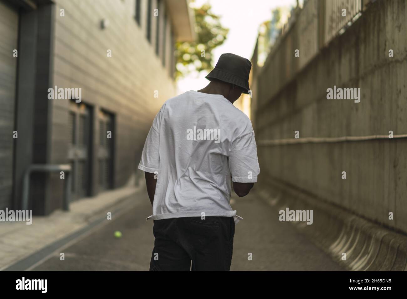 Back view of a cool young black male in a street style outfit walking ...