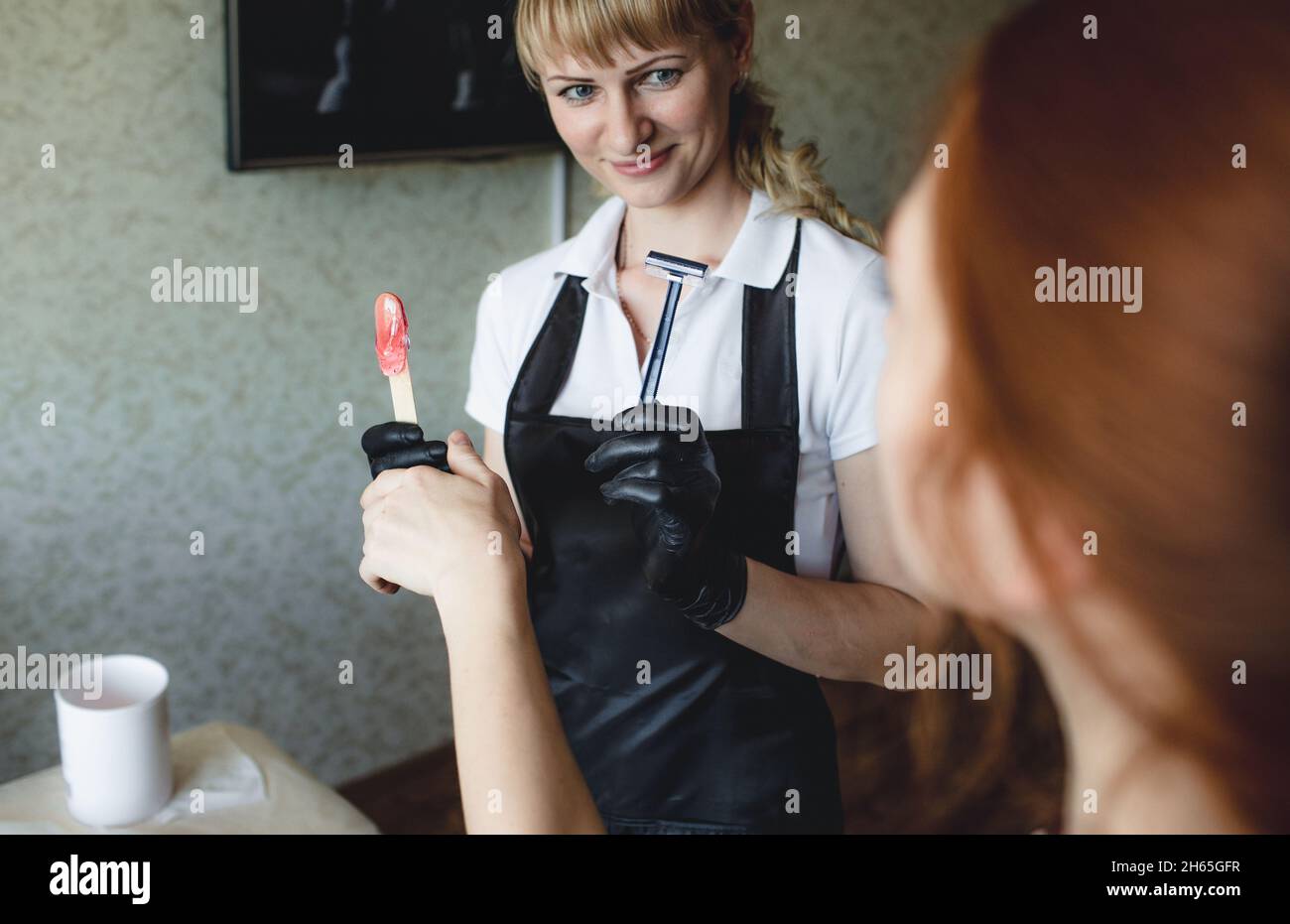 the depilation master stands in front of the client and holds a razor ...