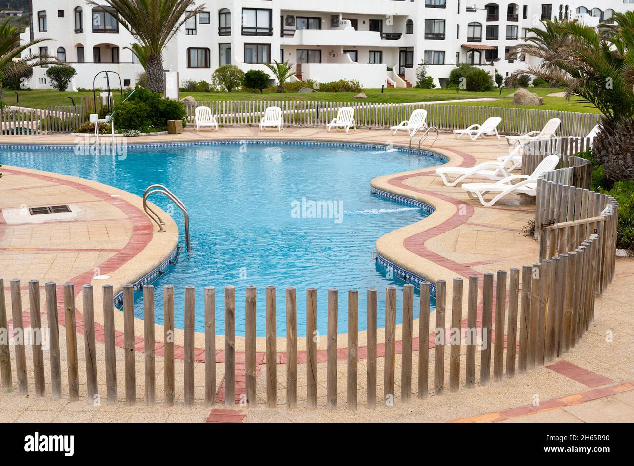 Empty swimming pool with sunbeds around by hotel. Pandemic lockdown ...