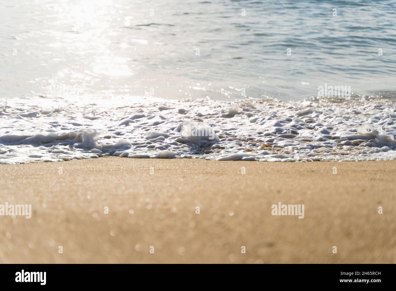 Sea wave by shore on beach with sun reflection on water. Natural ...