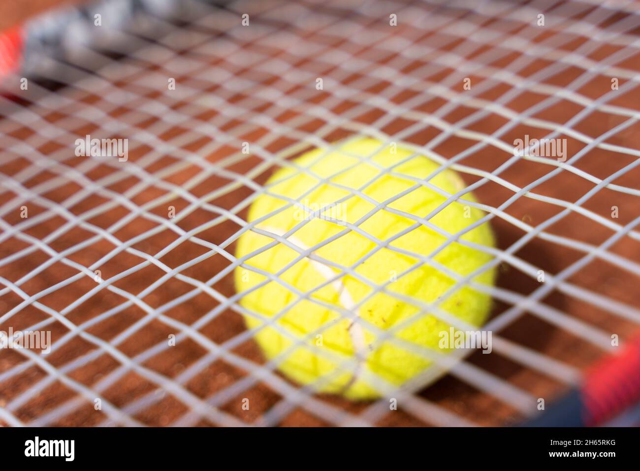 Tennis racket and ball under strings on clay court. Sports training ...
