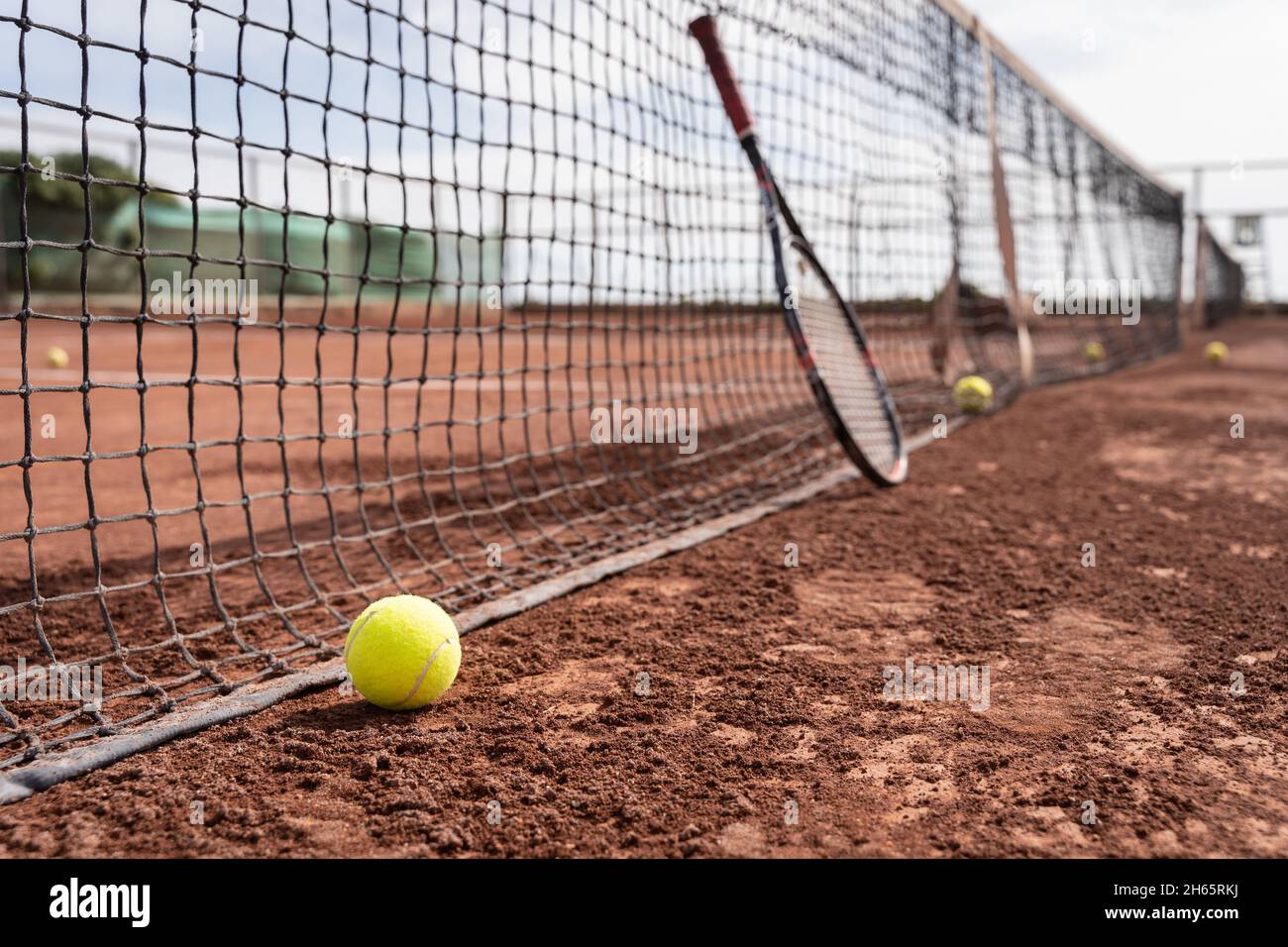Yellow tennis ball on clay court and racket leaning on net. Sport ...