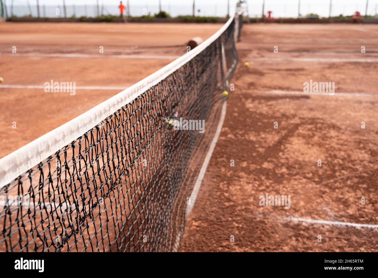 Tennis court net with racket and balls on clay floor outdoors. Sports ...