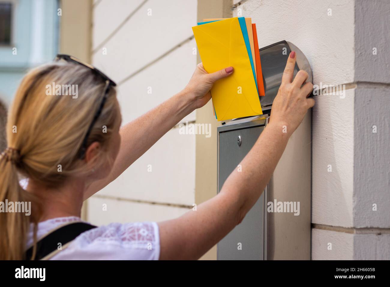Postal worker is inserting letters into mailbox. Woman is holding ...