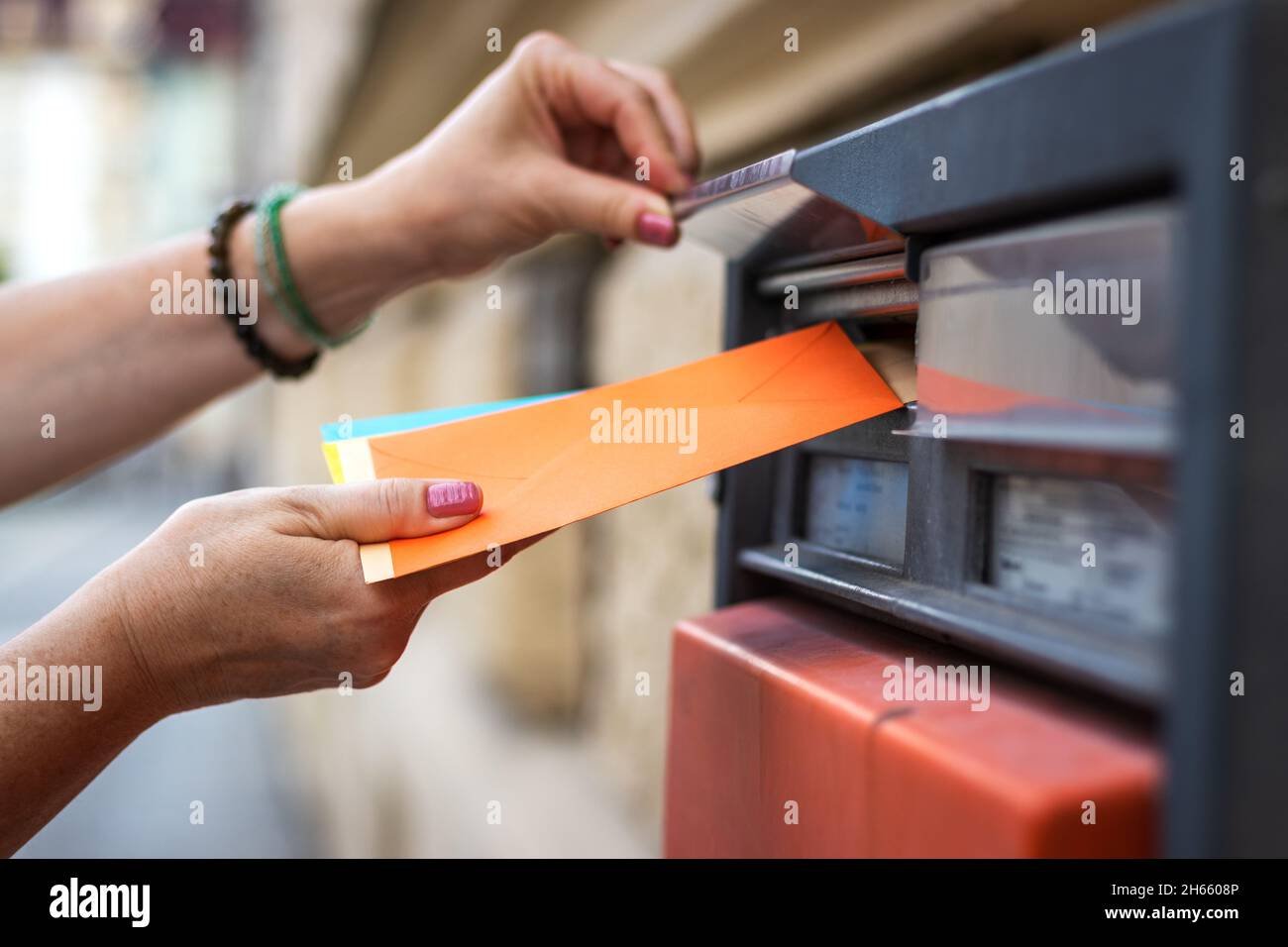 Sending letters by mail. Woman inserting envelope into public mailbox ...