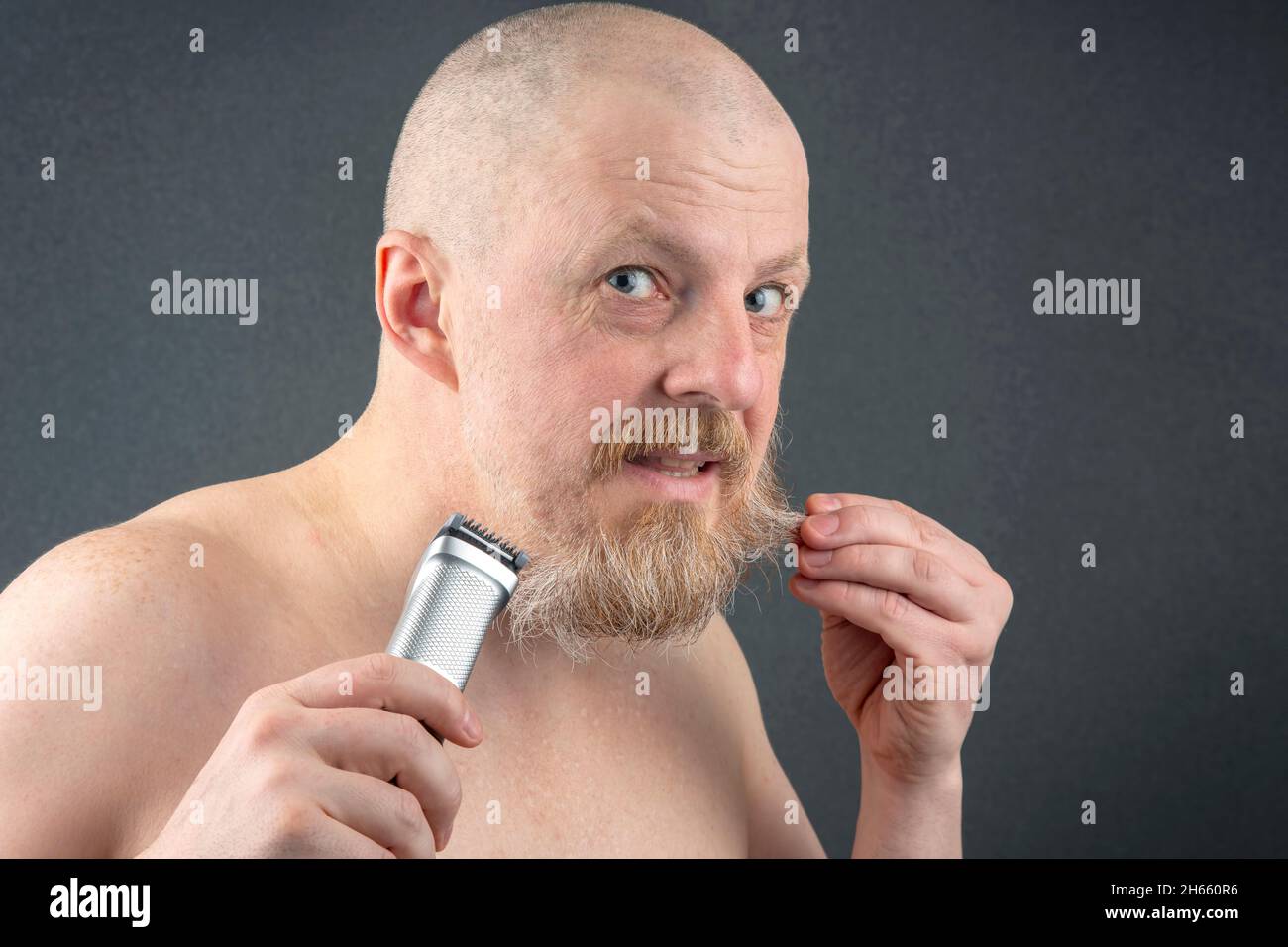 Bearded man with trimmer to adjust beard in hand. grooming and fashionable style barbershop ...