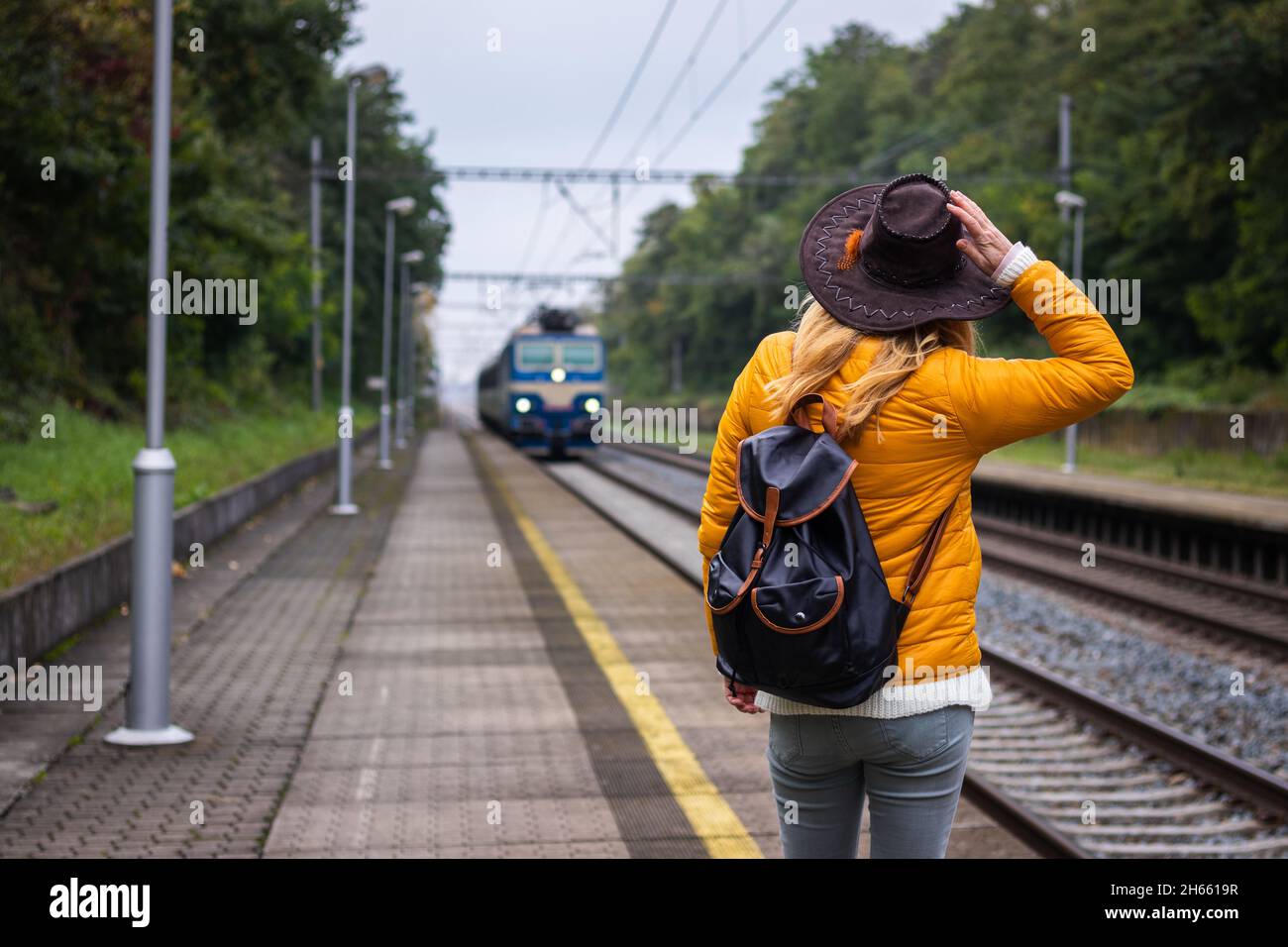 Traveler is looking at arriving train at railroad station platform ...