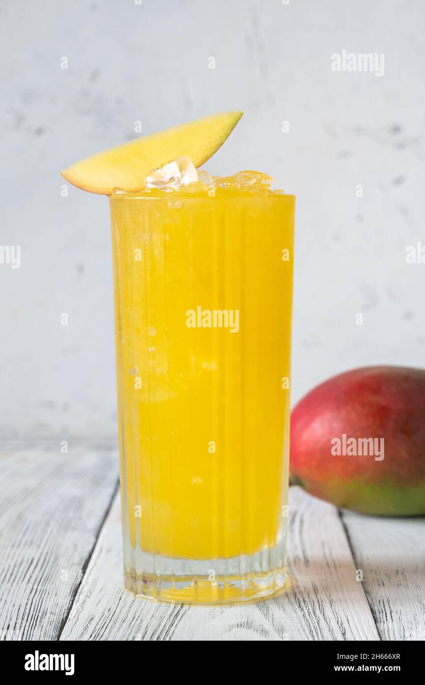 Glass of Mango Punch cocktail garnished with mango slice Stock Photo ...