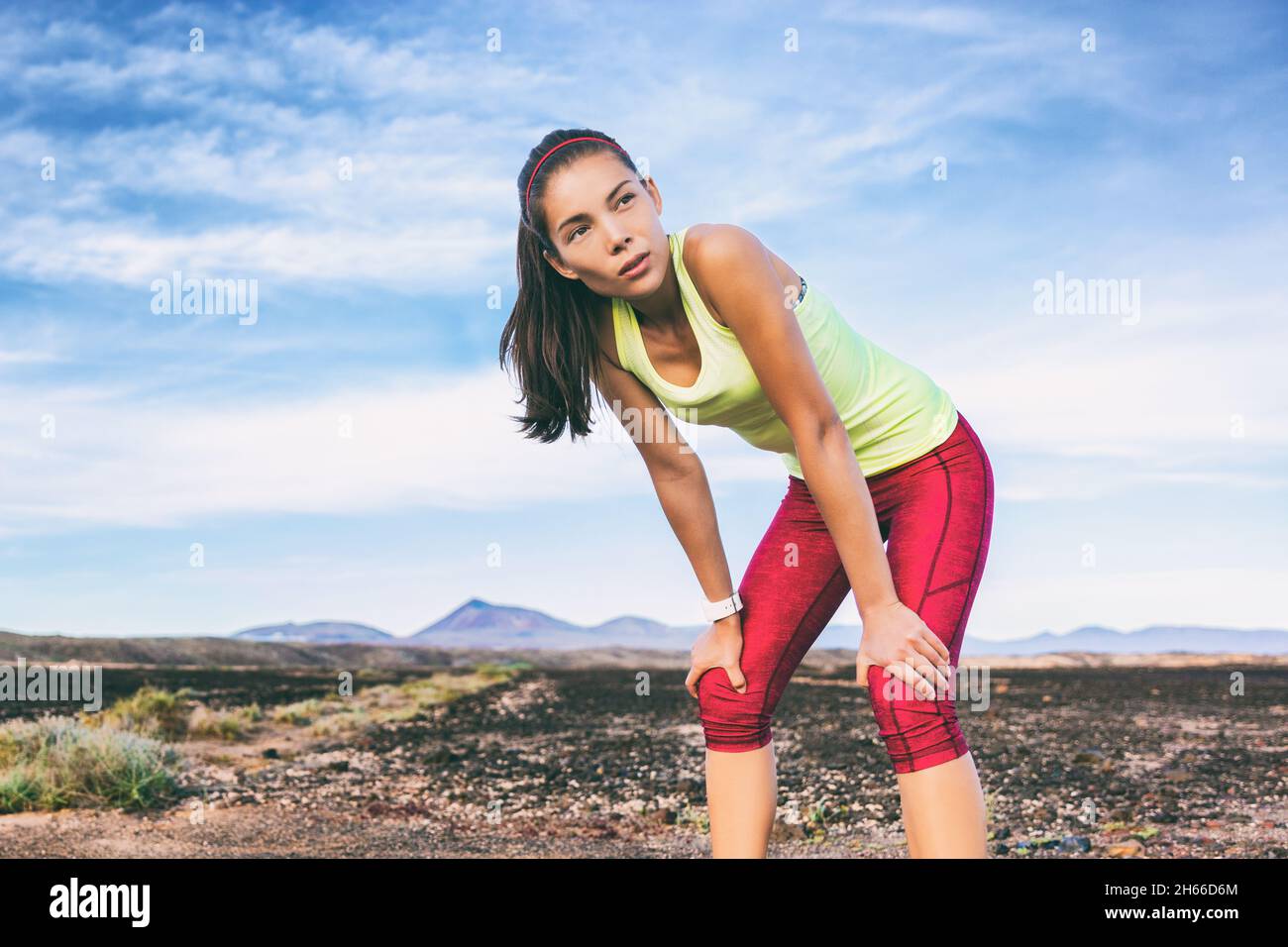 Tired runner girl taking a break breathing during jogging training ...